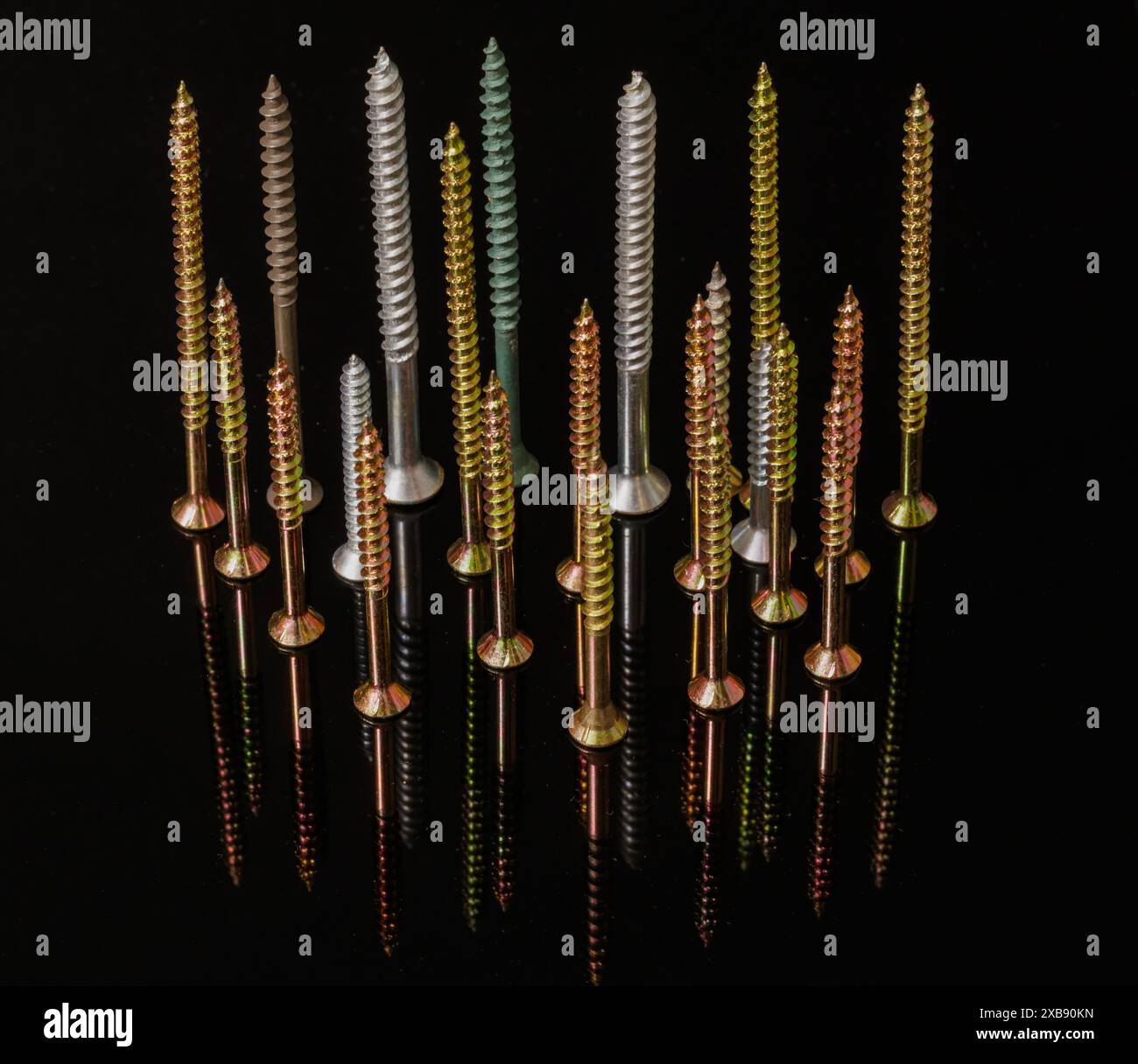 A variety of colorful and sized screws on a reflective surface Stock ...