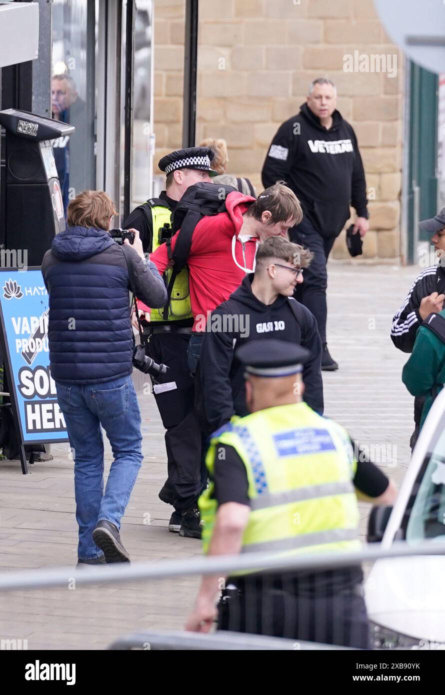 Police officers escort a person after he threw a cup towards Reform UK ...
