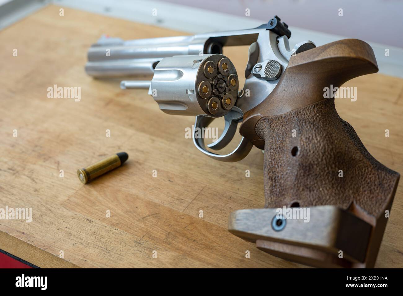drum of a revolver loaded with bullets. The gun is on a wooden table ...