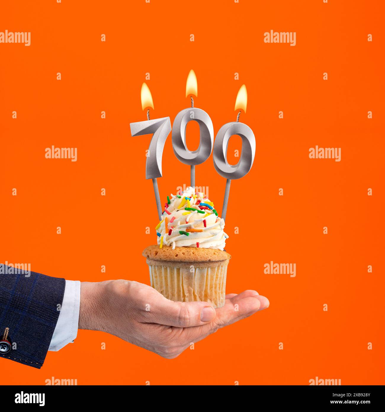 Hand holding birthday cupcake with number 700 candle - background ...