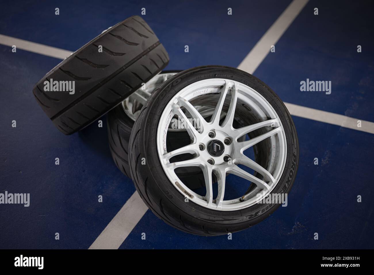 A closeup of three sports car wheels stacked on the parking lot floor ...
