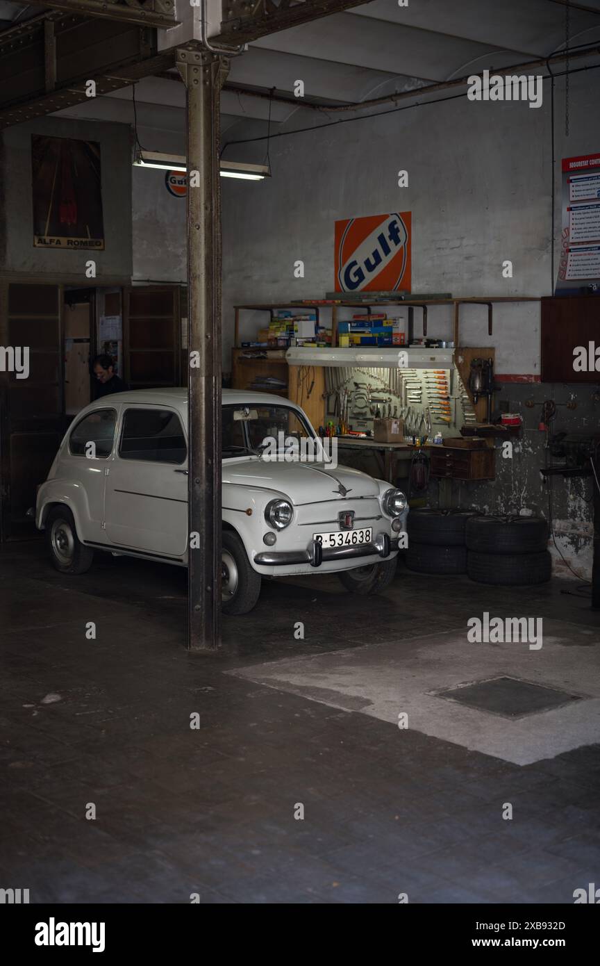 A vertical shot of an old car mechanic workshop with a white Seat 600 ...