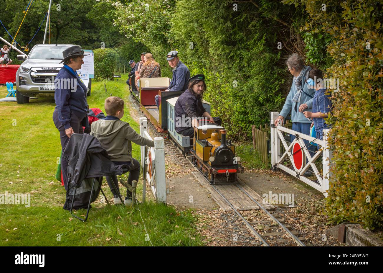 People watch a minature narrow gauge steam train carrying passengers ...