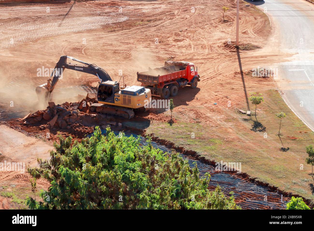 An Excavator digging up the ground and loading dirt into a dump truck ...