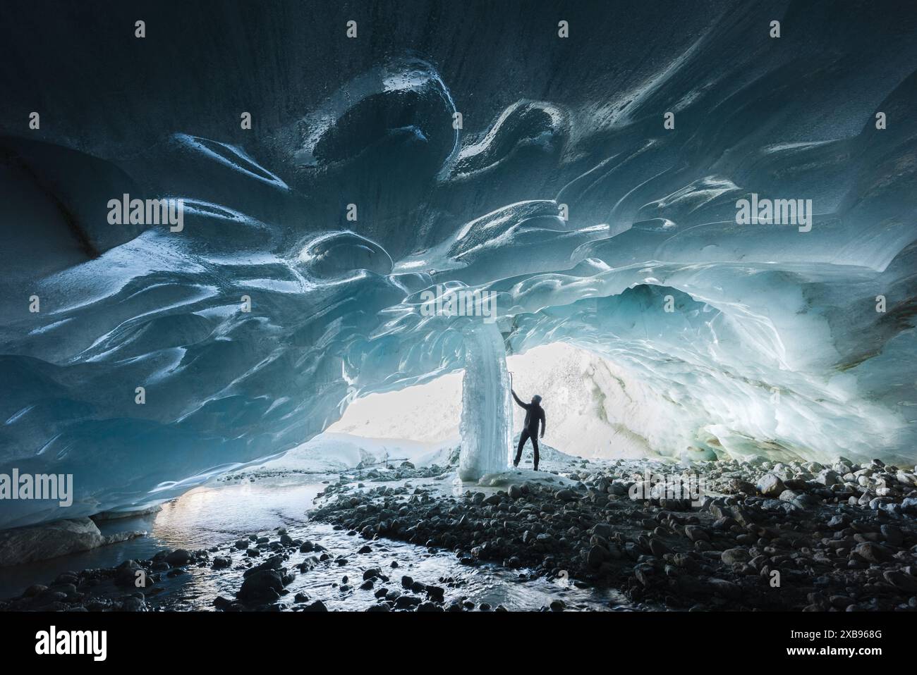 Winter landscape view of an alpinist exploring an ice cave with a ...