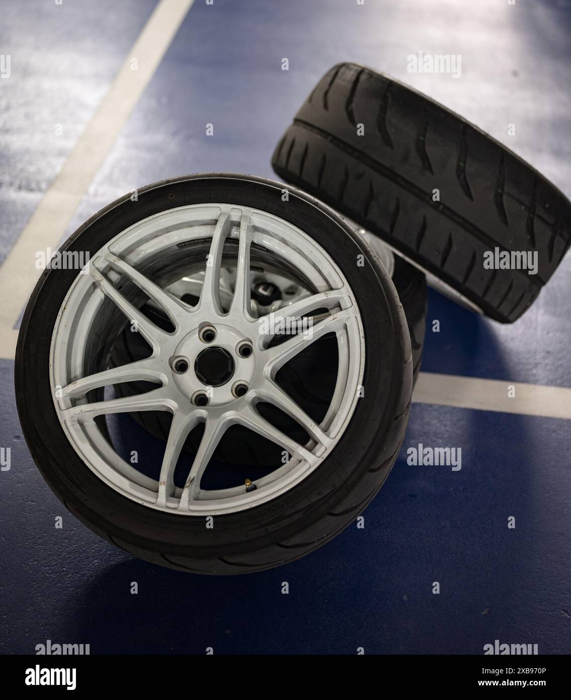 Detail of three sports car wheels stacked on the parking lot floor ...