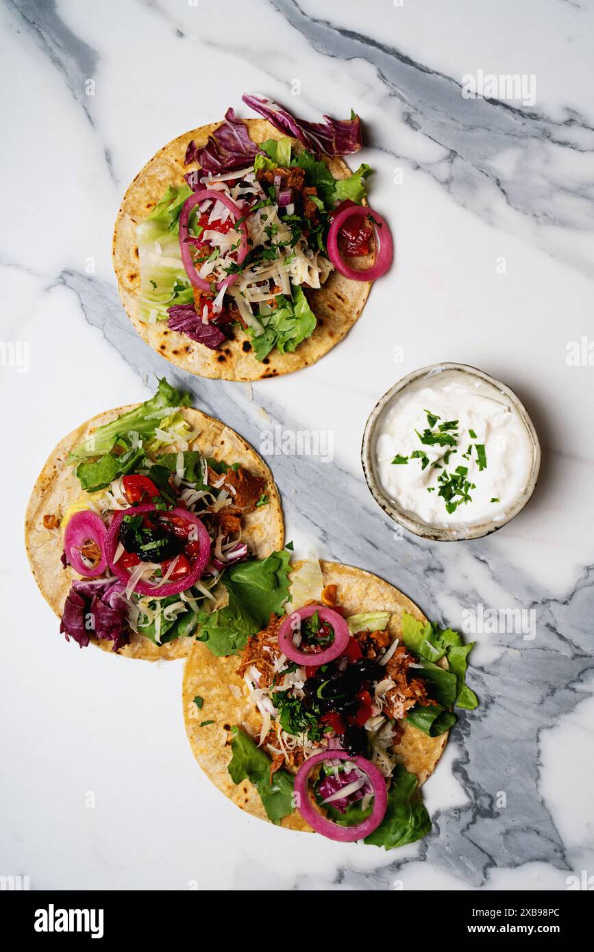 Three tacos with mixed greens, pickled onions, and shredded cheese ...