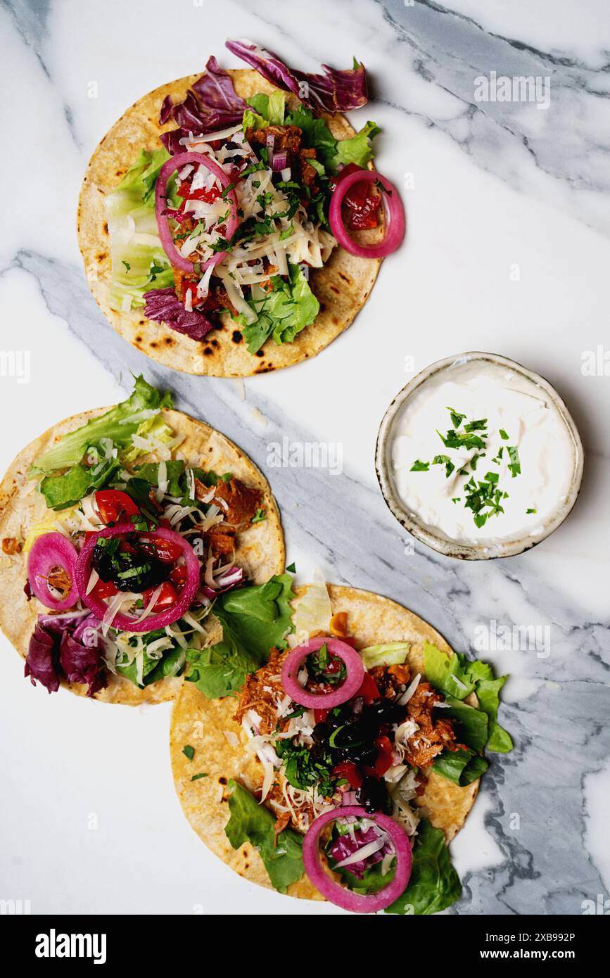 Three tacos with mixed greens, pickled onions, and shredded cheese ...