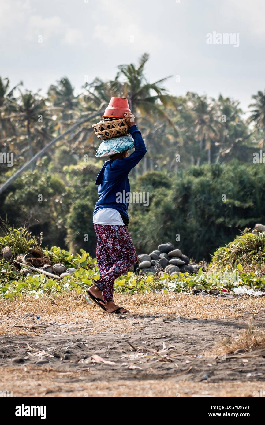 A local woman balancing a basket on her head near Abian Kapas Beach ...