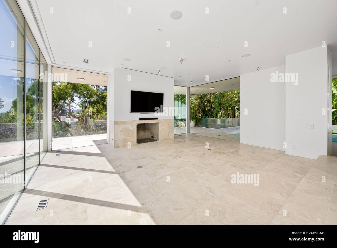 A spacious living room with high ceiling, glass doors, and TV mounted ...