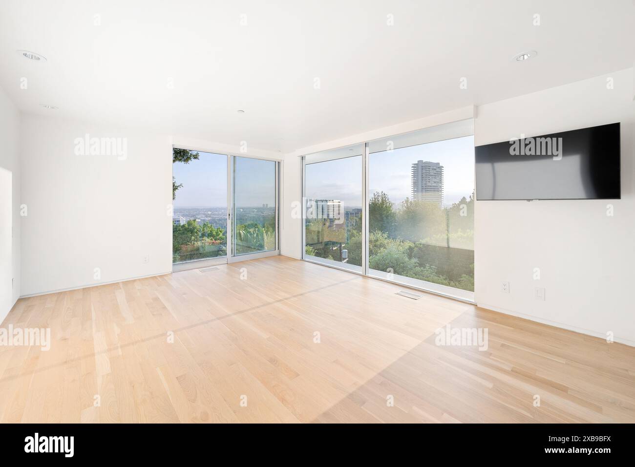A living room with a wide sliding glass door opening to a cityscape ...