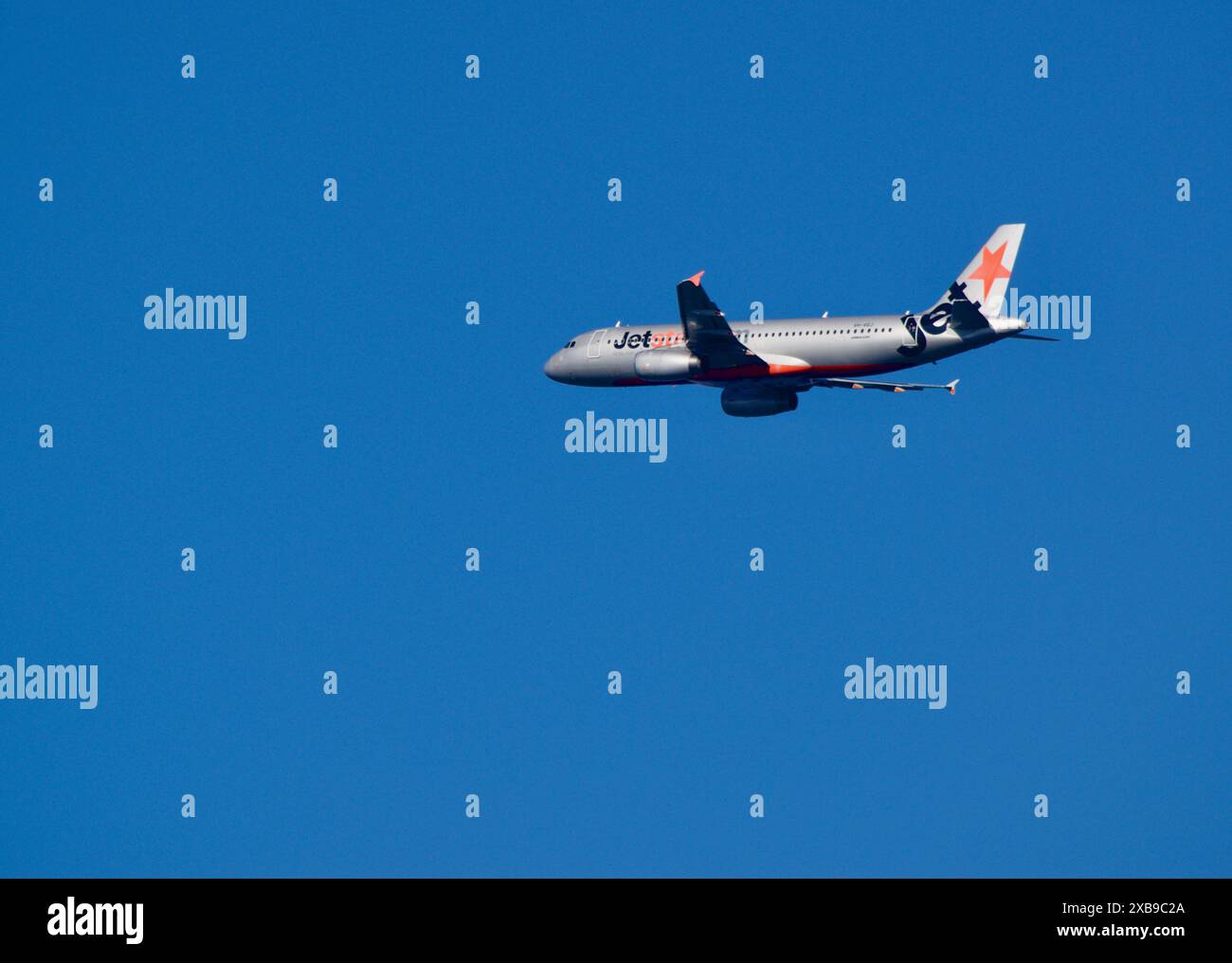 A Jetstar Airways airplane flying against a clear blue sky after taking ...