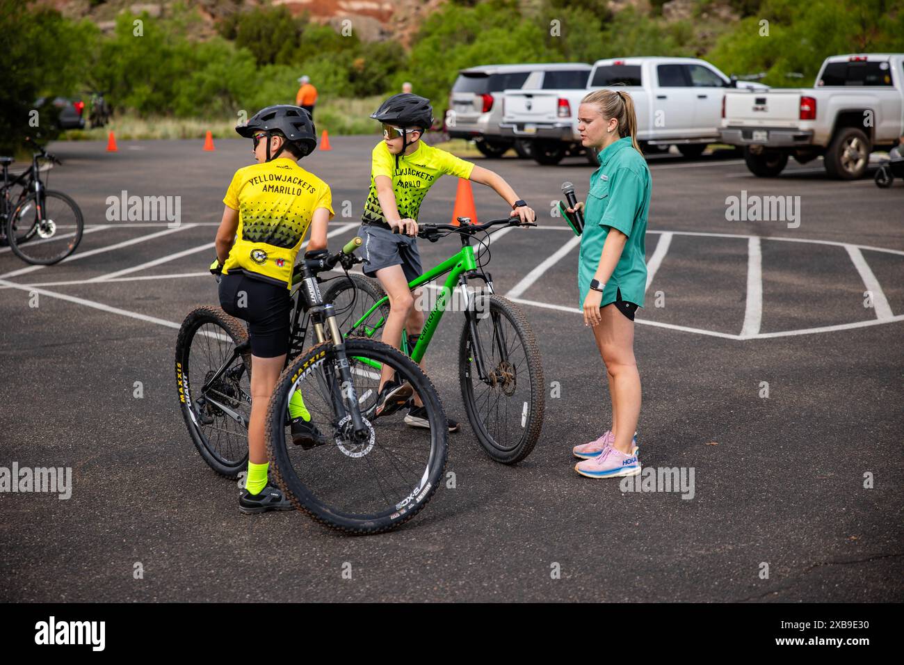 The young cyclists in yellow jerseys talking to a coach in a parking ...