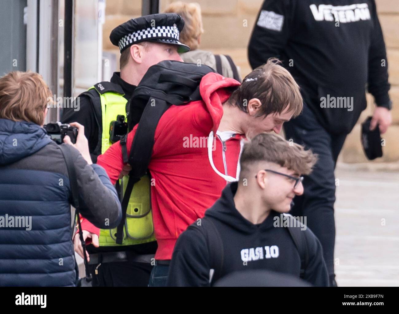 Police officers escort a person after he threw a cup towards Reform UK ...
