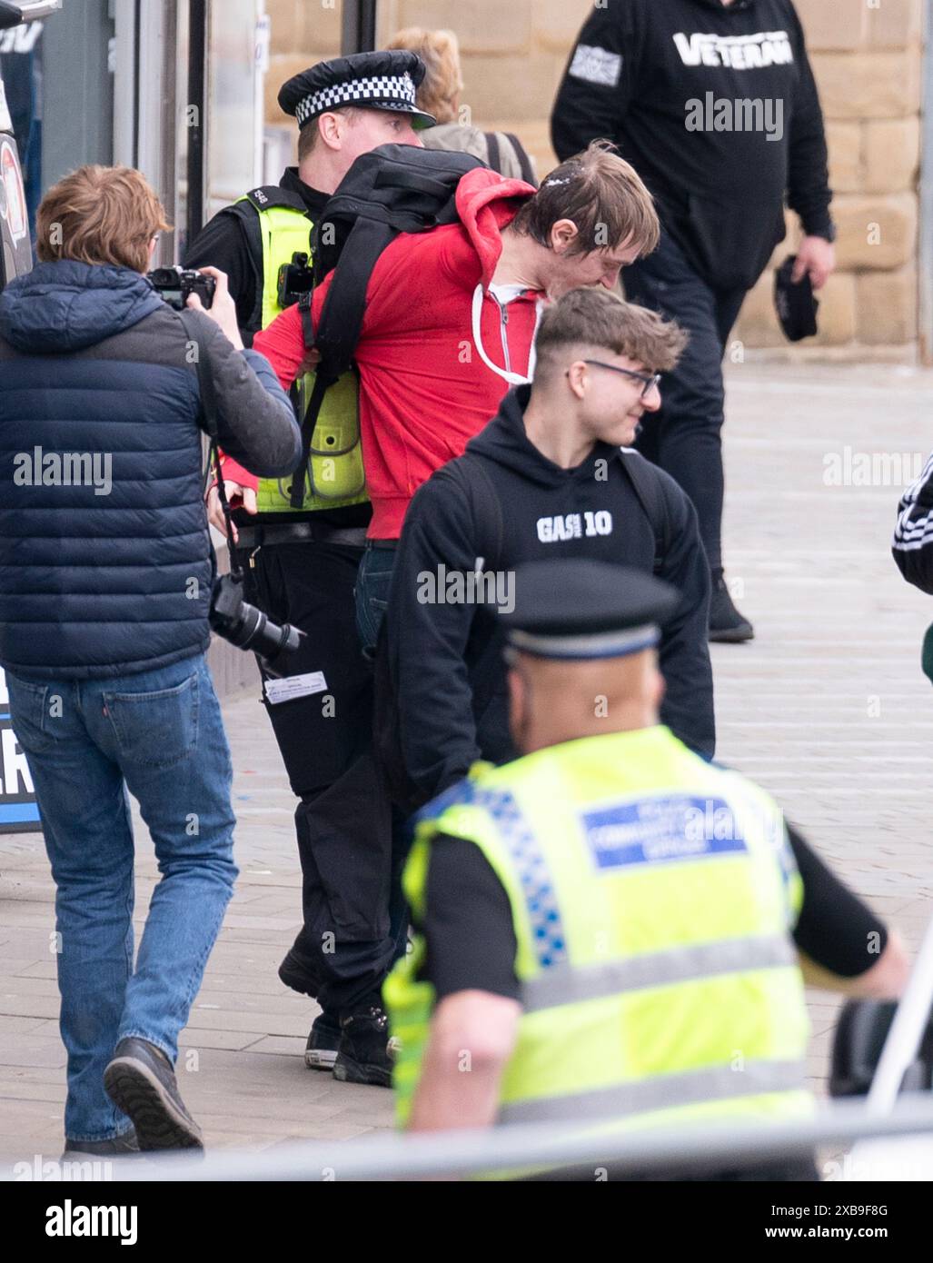 Police officers escort a person after he threw a cup towards Reform UK ...