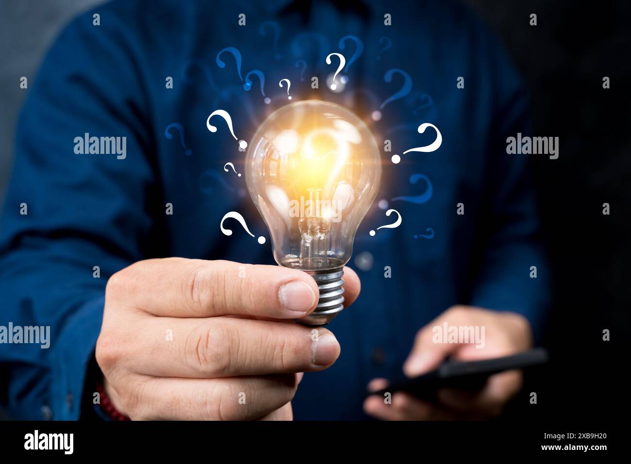 Businessman holding glowing lightbulb and question mark with copy space for creative thinking ...
