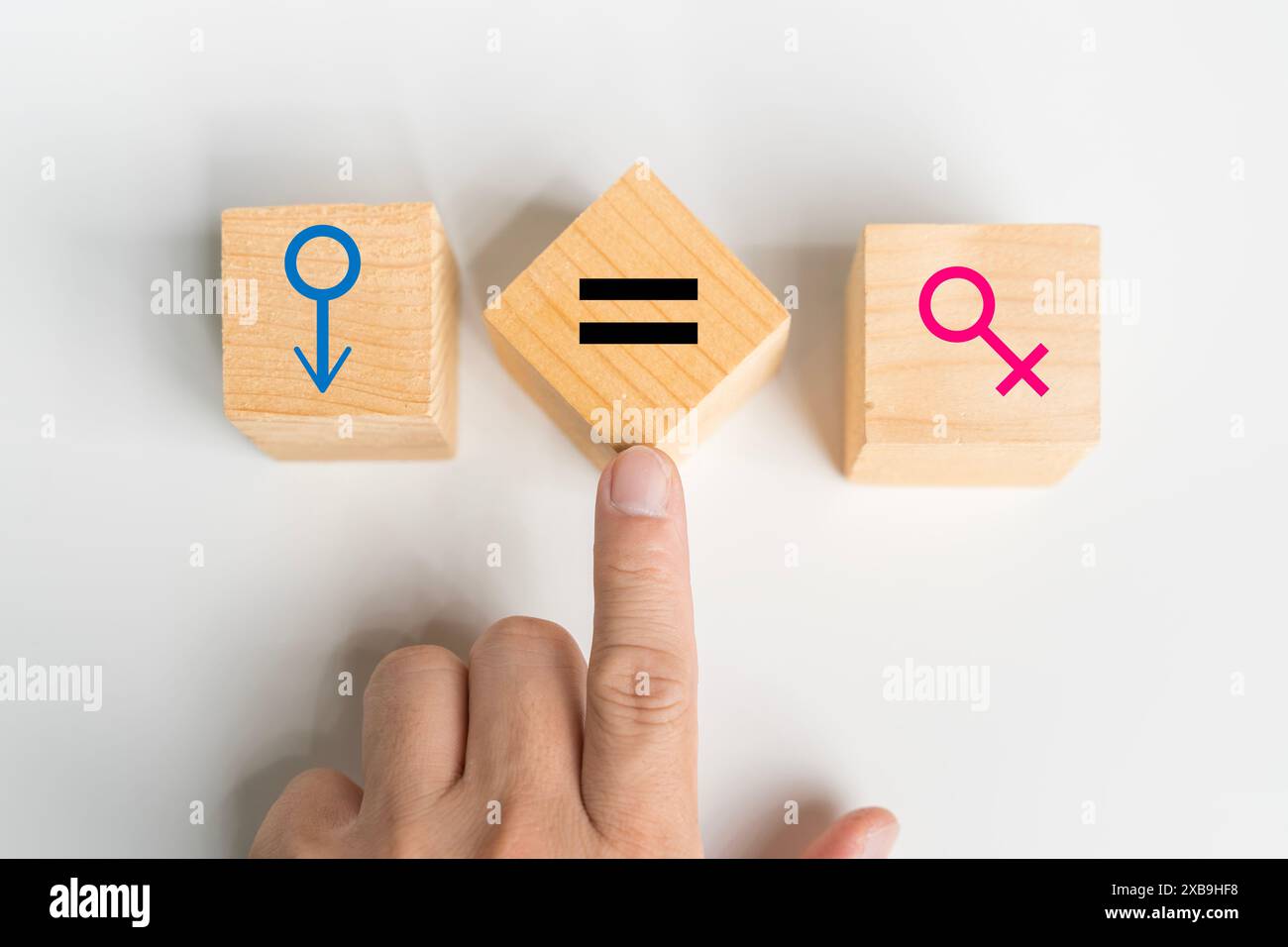 Hand touching wooden block with icons men and women for equality ...