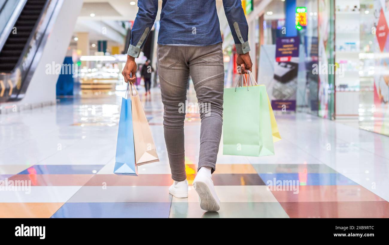Man Walking Down a Mall With Shopping Bags, Back View Stock Photo - Alamy