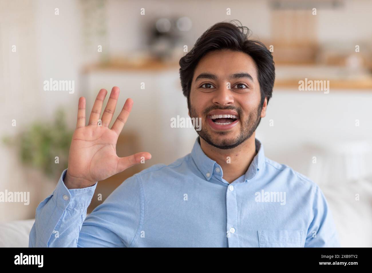 Happy Man Waving Hello in a Casual Setting Stock Photo - Alamy