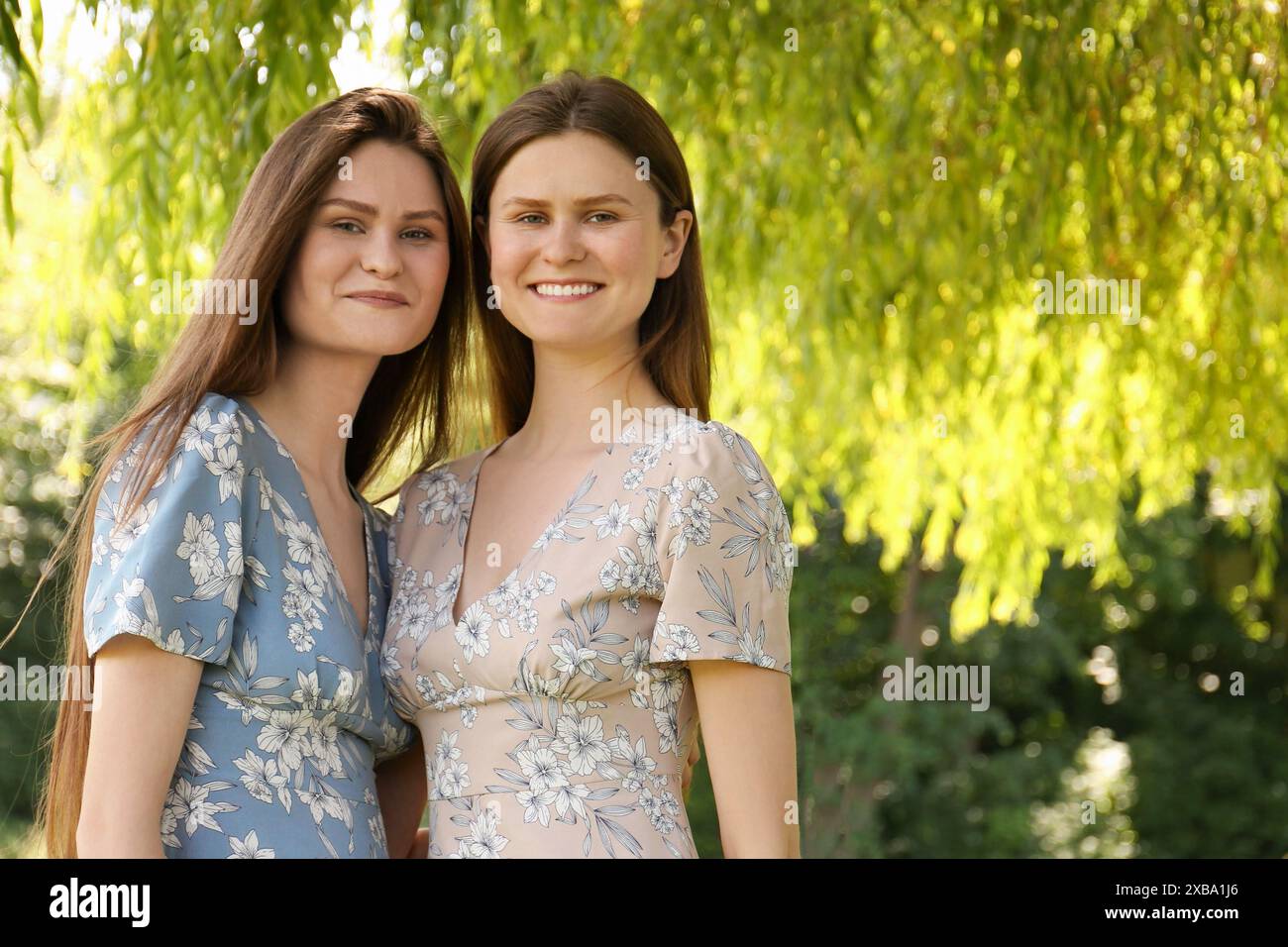 Portrait of two beautiful twin sisters in park, space for text Stock ...