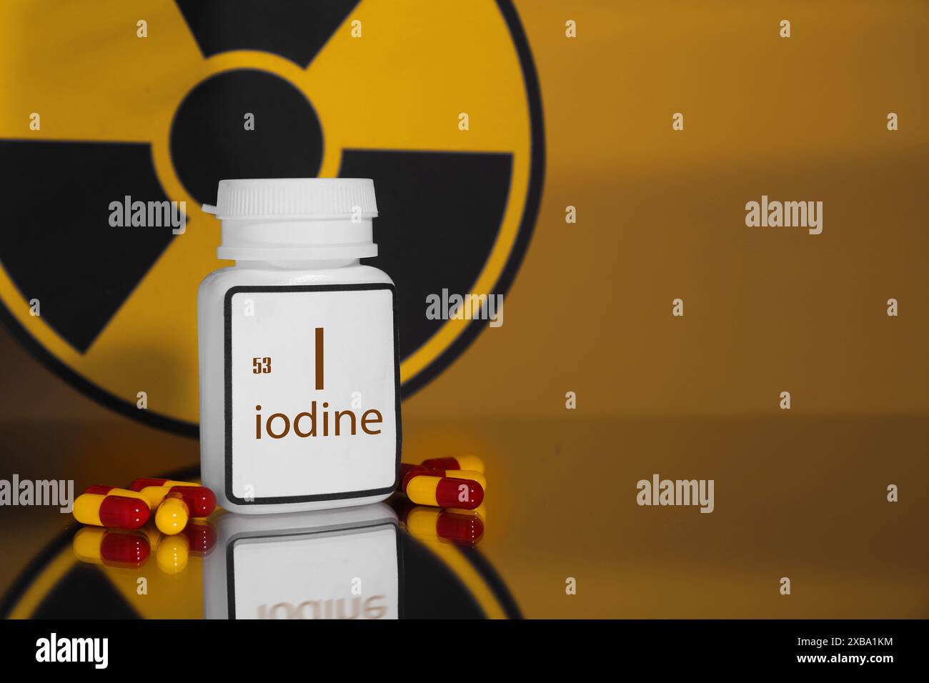 Bottle of medical iodine capsules and radiation sign on orange ...