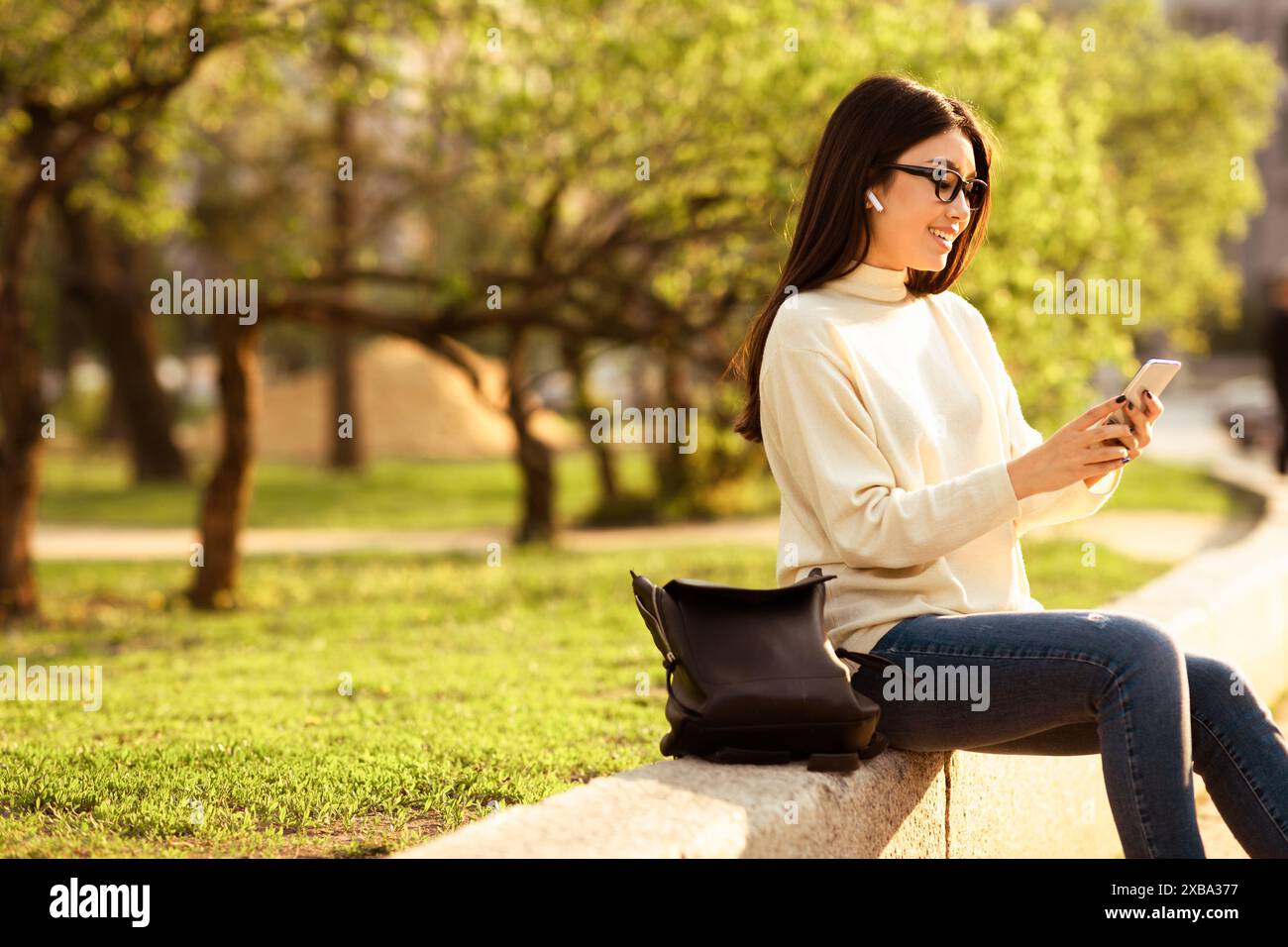 Woman scrolling phone on bench hi-res stock photography and images - Alamy