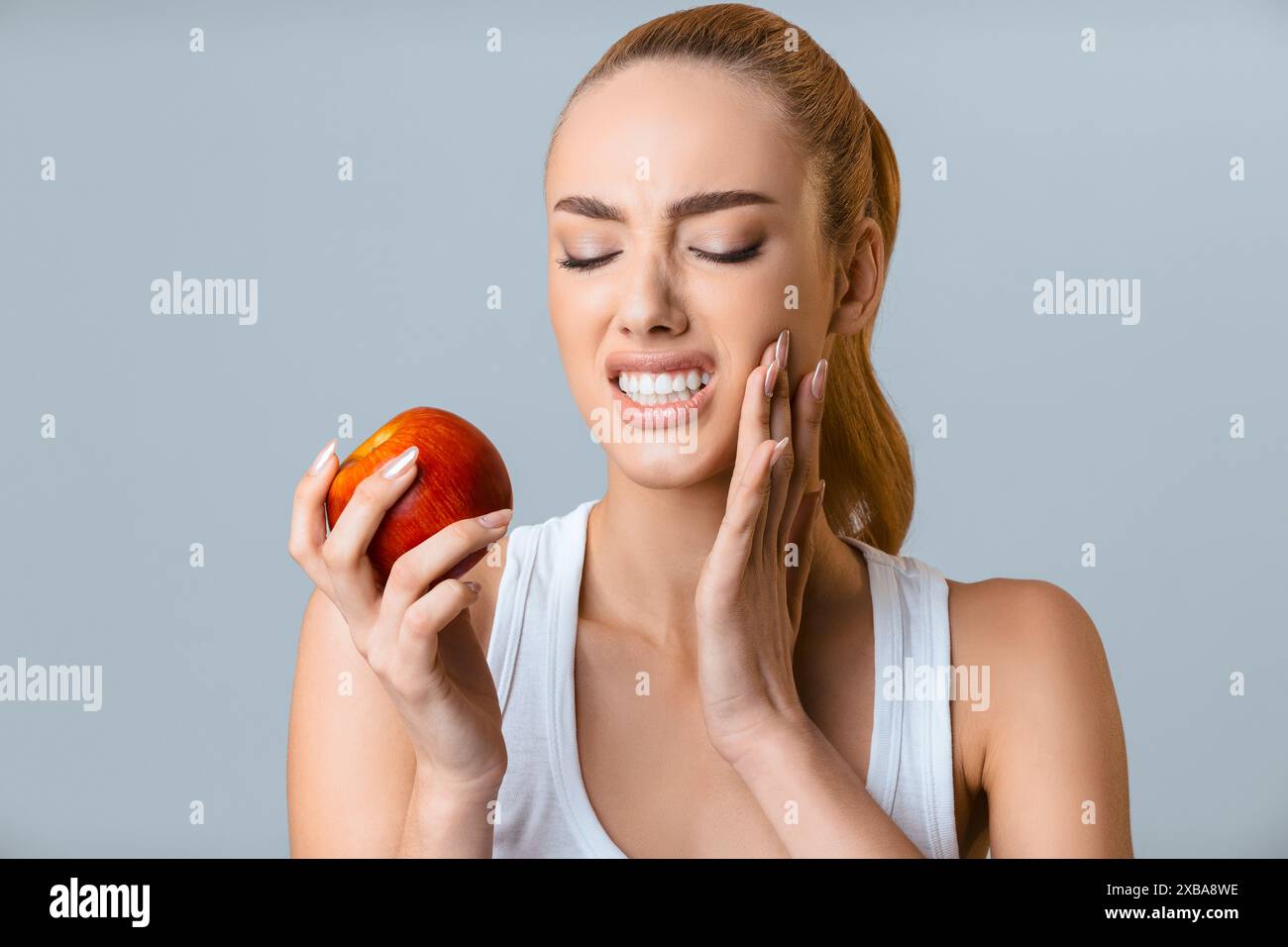 Tooth problems. Young woman having toothache, biting apple Stock Photo - Alamy