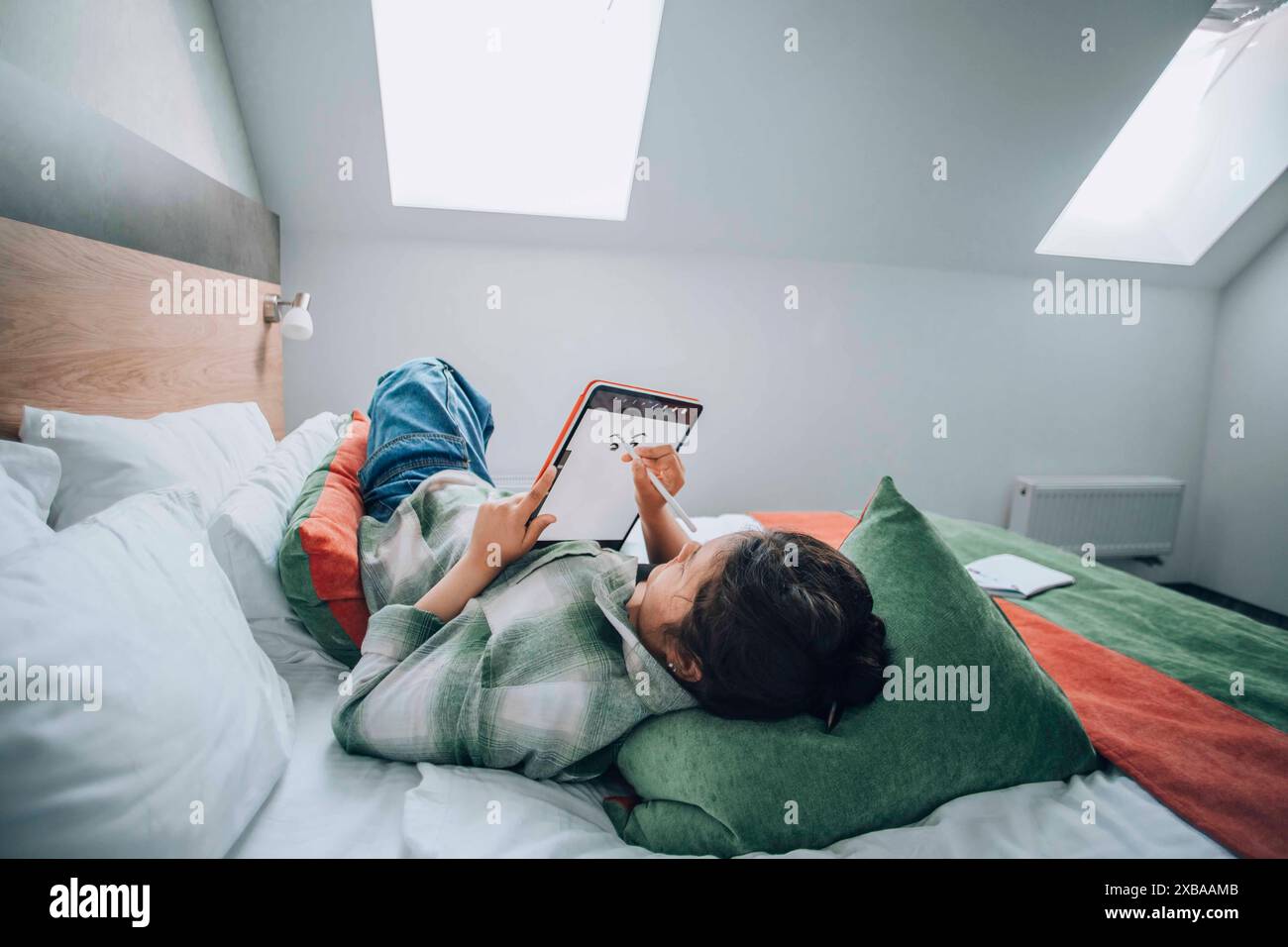 In the quiet comfort of her bedroom, a girl uses her tablet to sketch ...