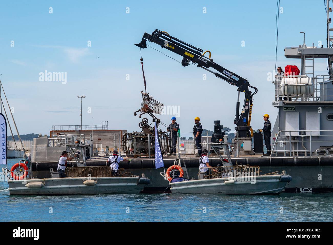 Recovered waste is hoisted onto a hybrid-powered military barge as part ...