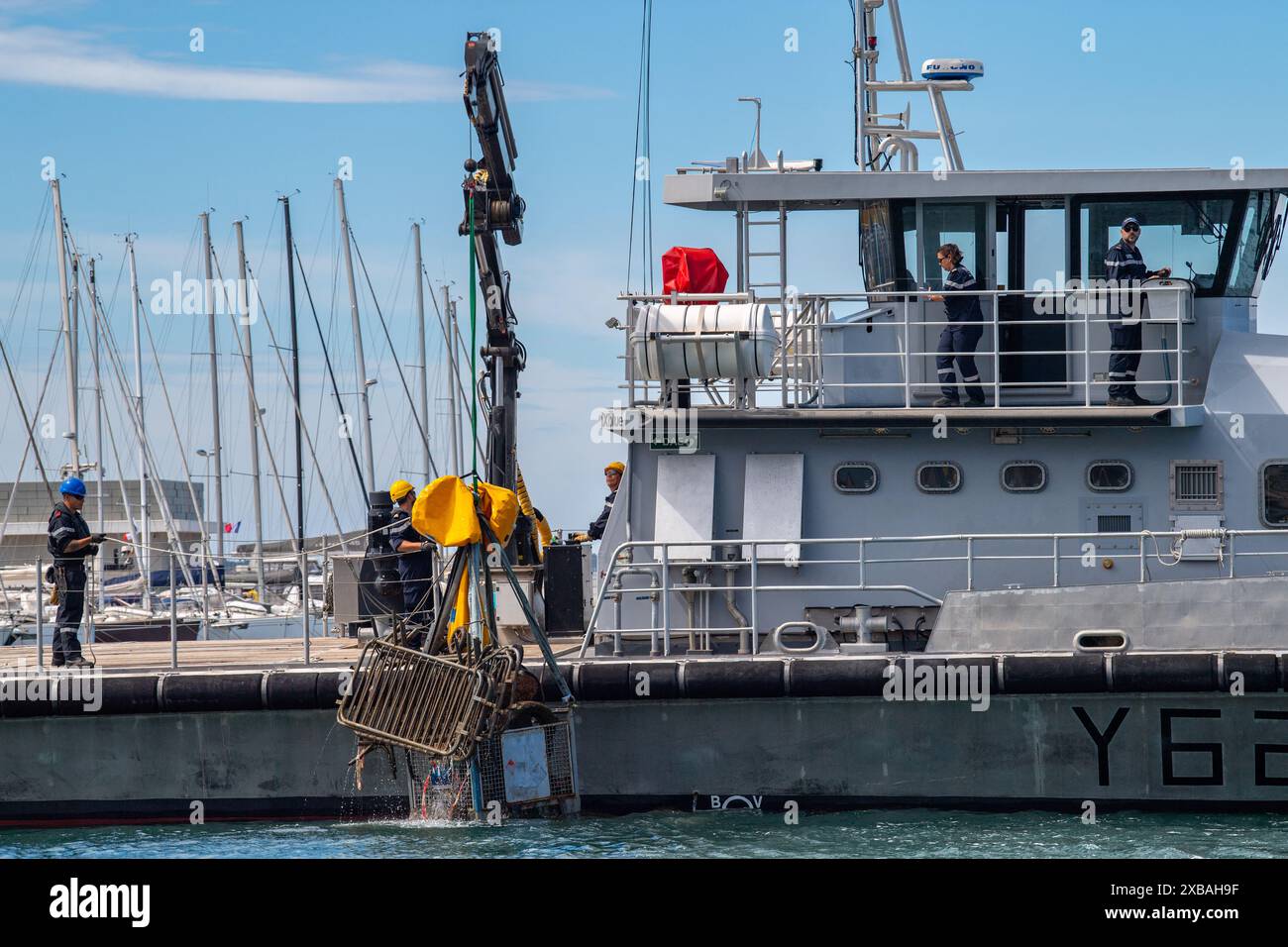 Recovered waste is hoisted onto a hybrid-powered military barge as part ...