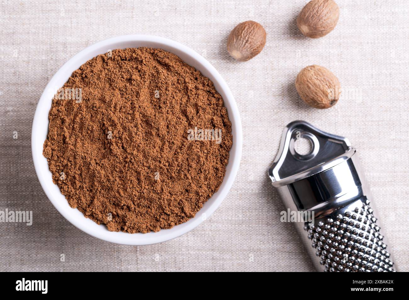 Nutmeg powder, ground nutmeg in a white bowl on linen fabric. Fragrant ...