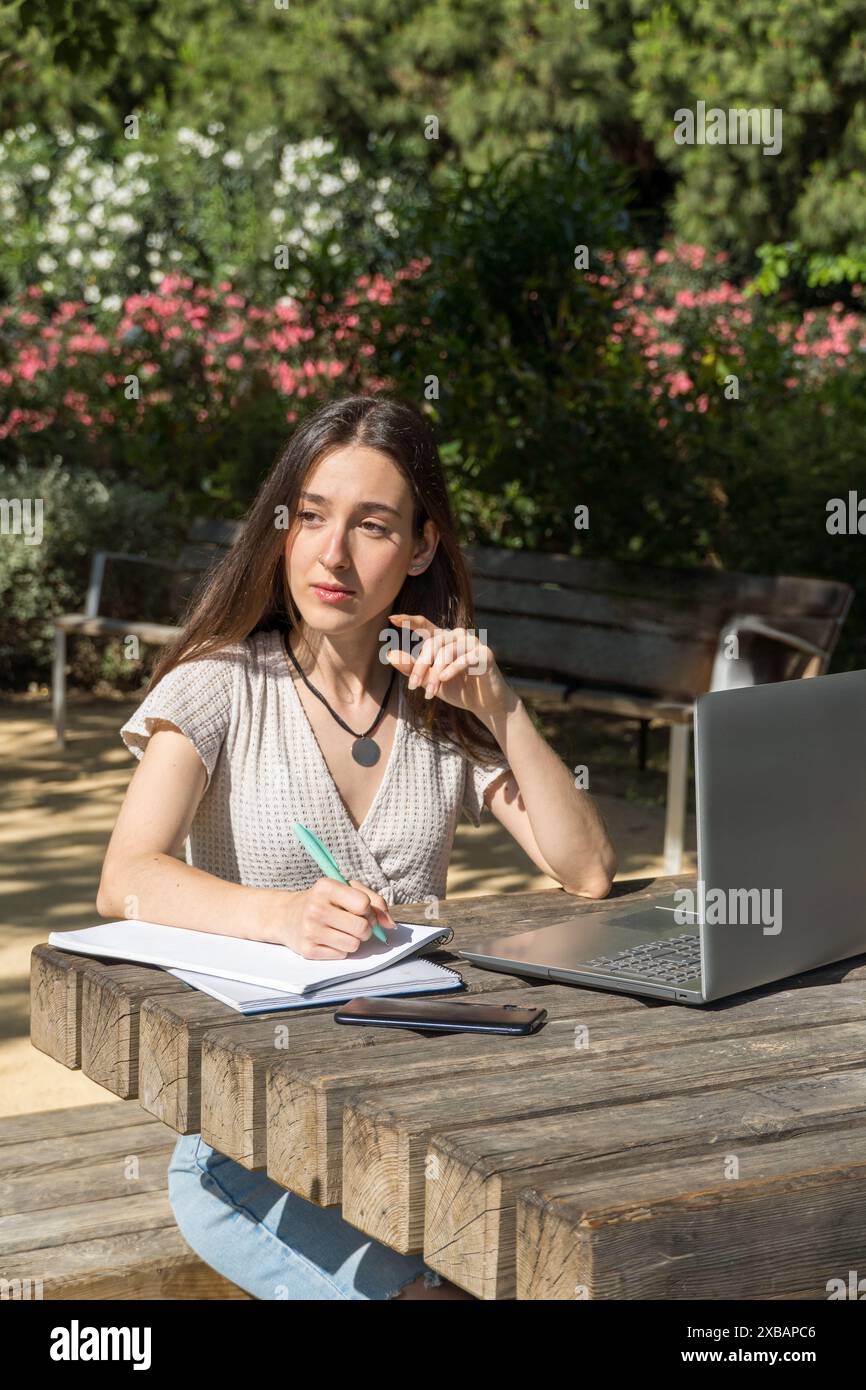 Young college student with thoughtful expression, using her laptop at a ...