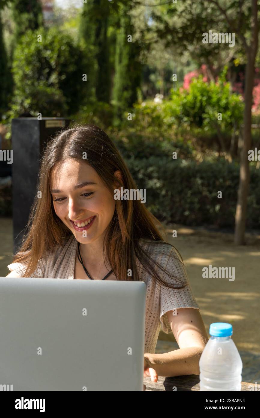 Young student on university campus, concentrating using her laptop ...