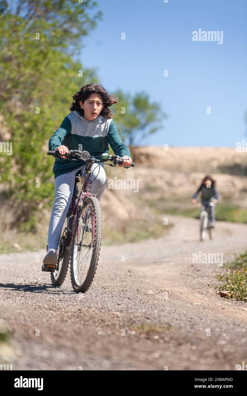 Teen boy on bike going down a winding way. In the background out of ...