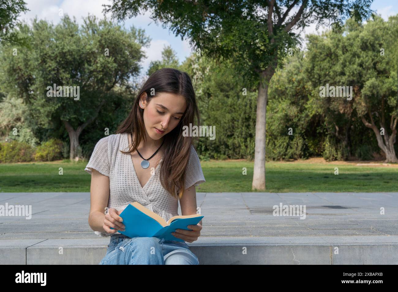 Lovely young college girl enjoying a book on campus. Relaxed, focused ...