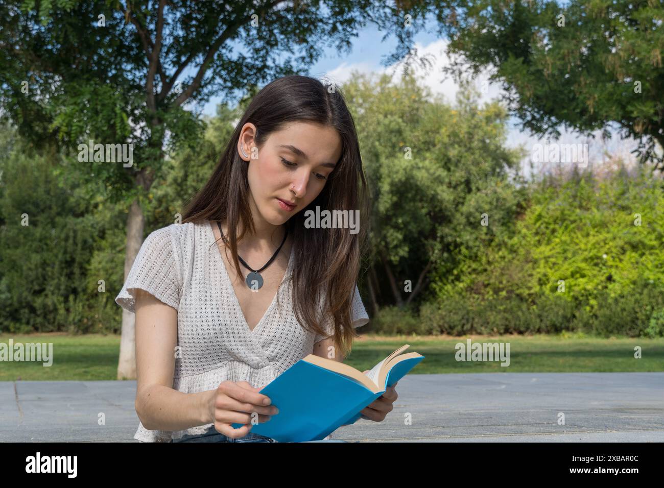 College student taking a break on campus, reading a book with ...