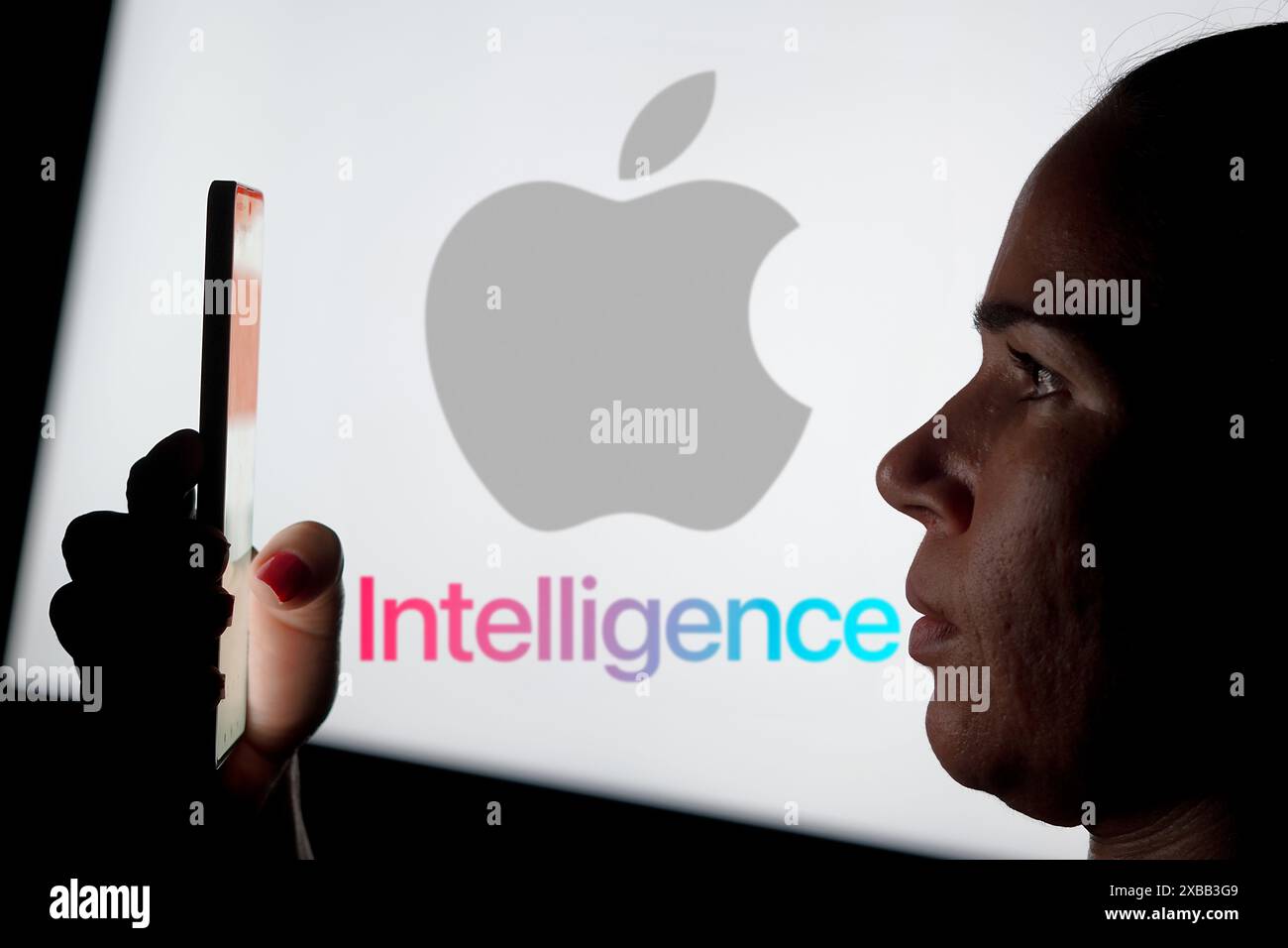 In this photo illustration, a woman holding a smartphone and the Apple Intelligence logo is seen ...