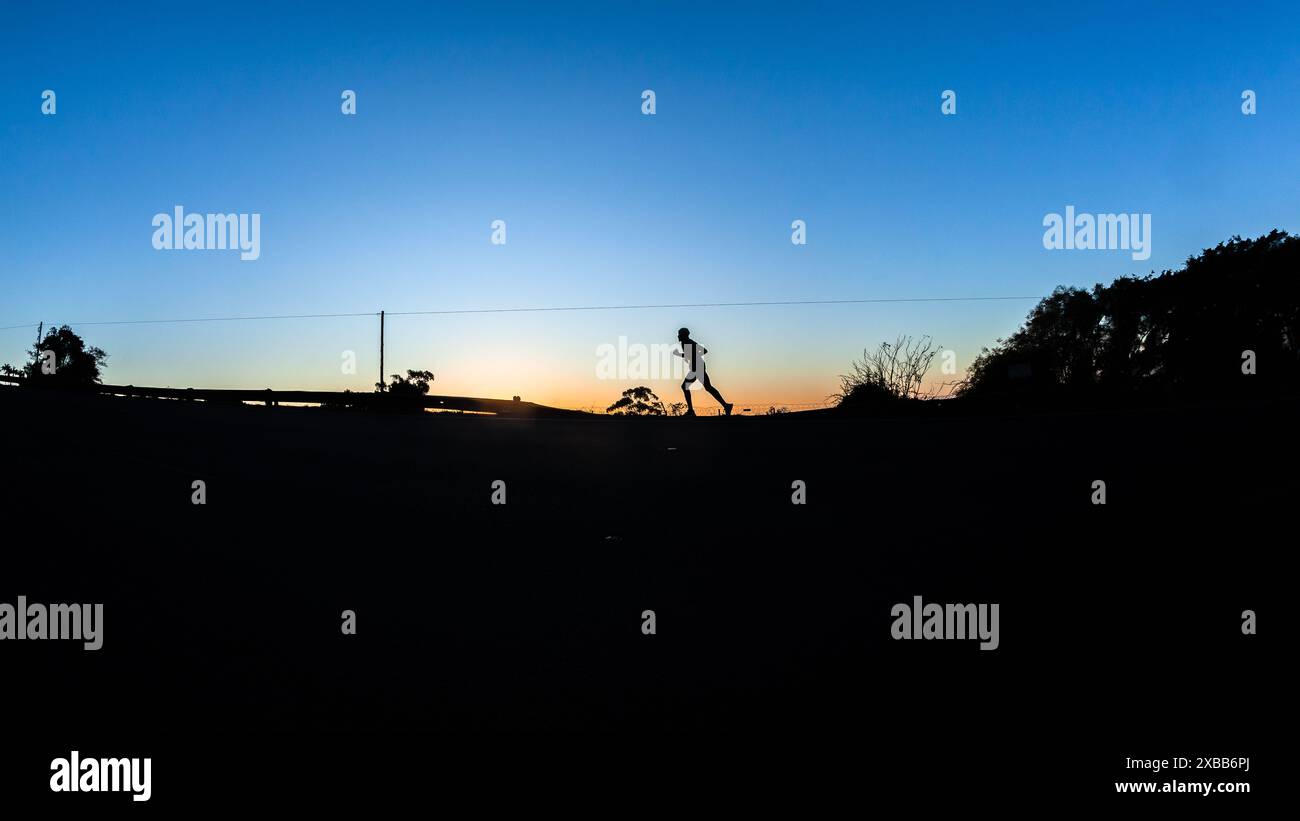 Marathon runners silhouetted morning dawn sunrise running up hill in ...