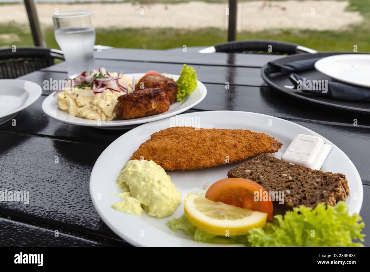 Seafood restaurant on the seashore. White plate with fish patties, fish ...