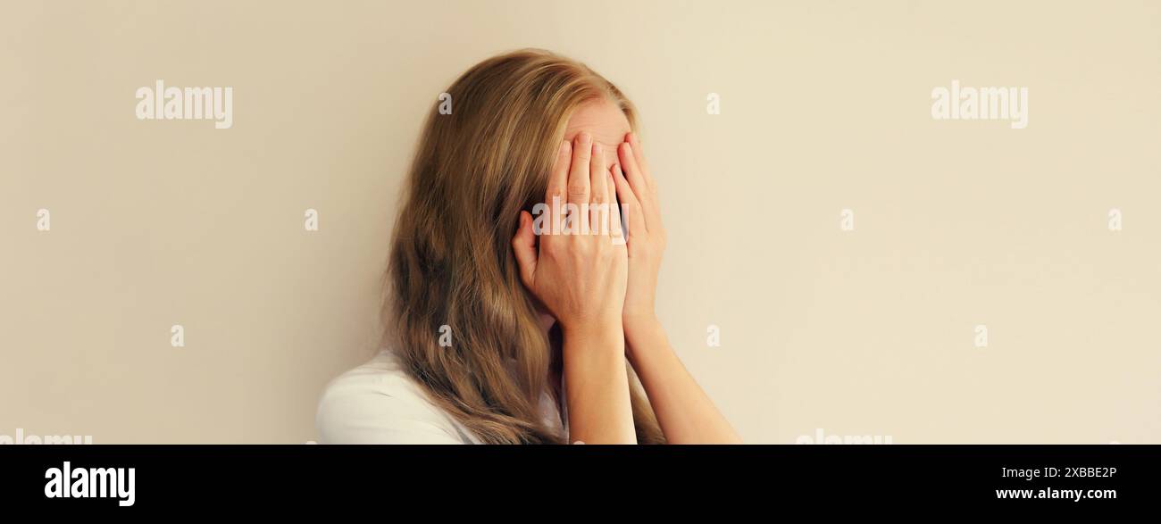 Upset sad crying woman covering her eyes and face with hands while ...
