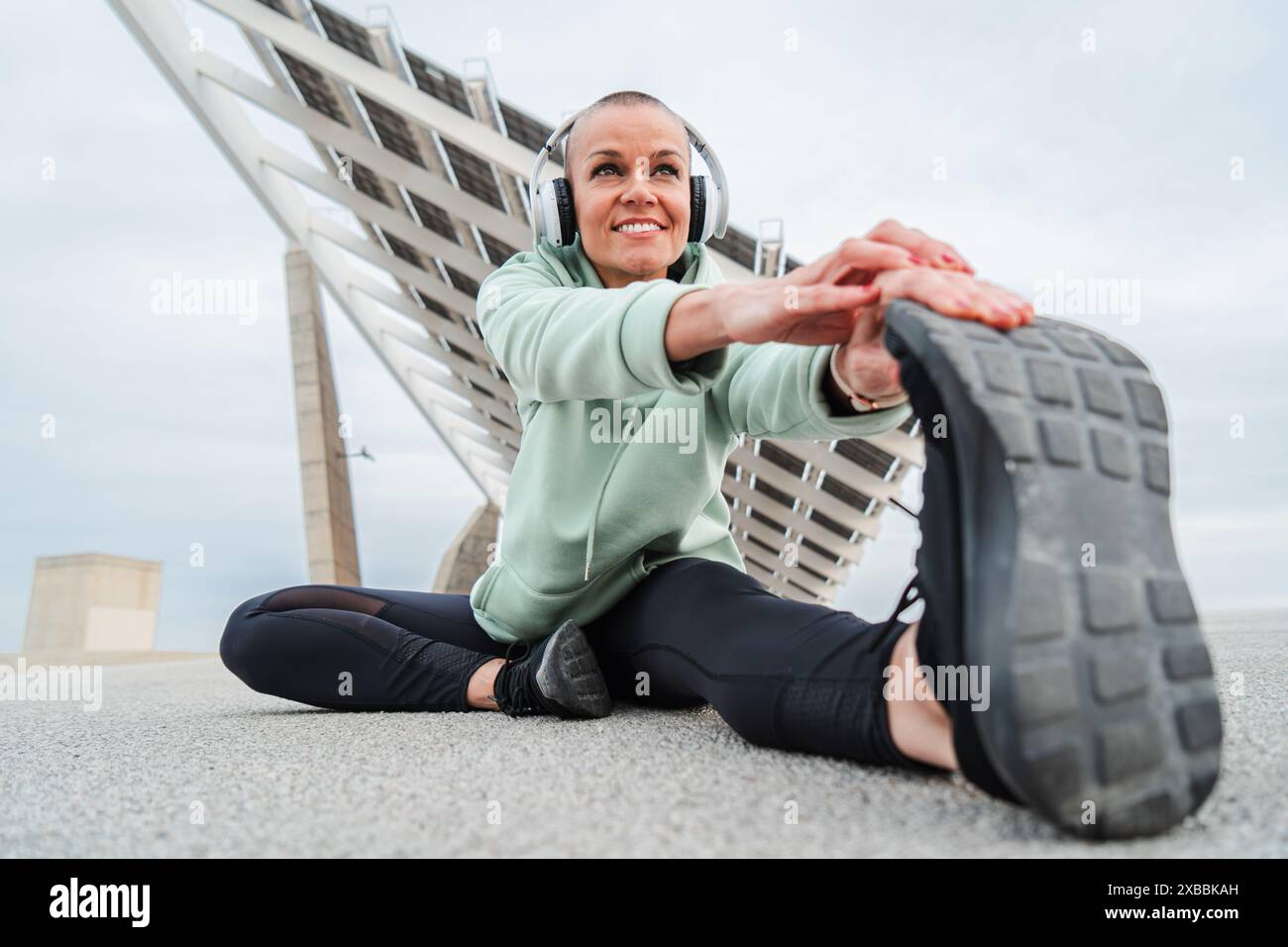 Mid adult strong woman stretching the muscle of her leg after running ...