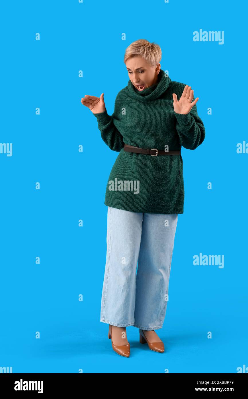 Scared mature woman on light blue background Stock Photo - Alamy