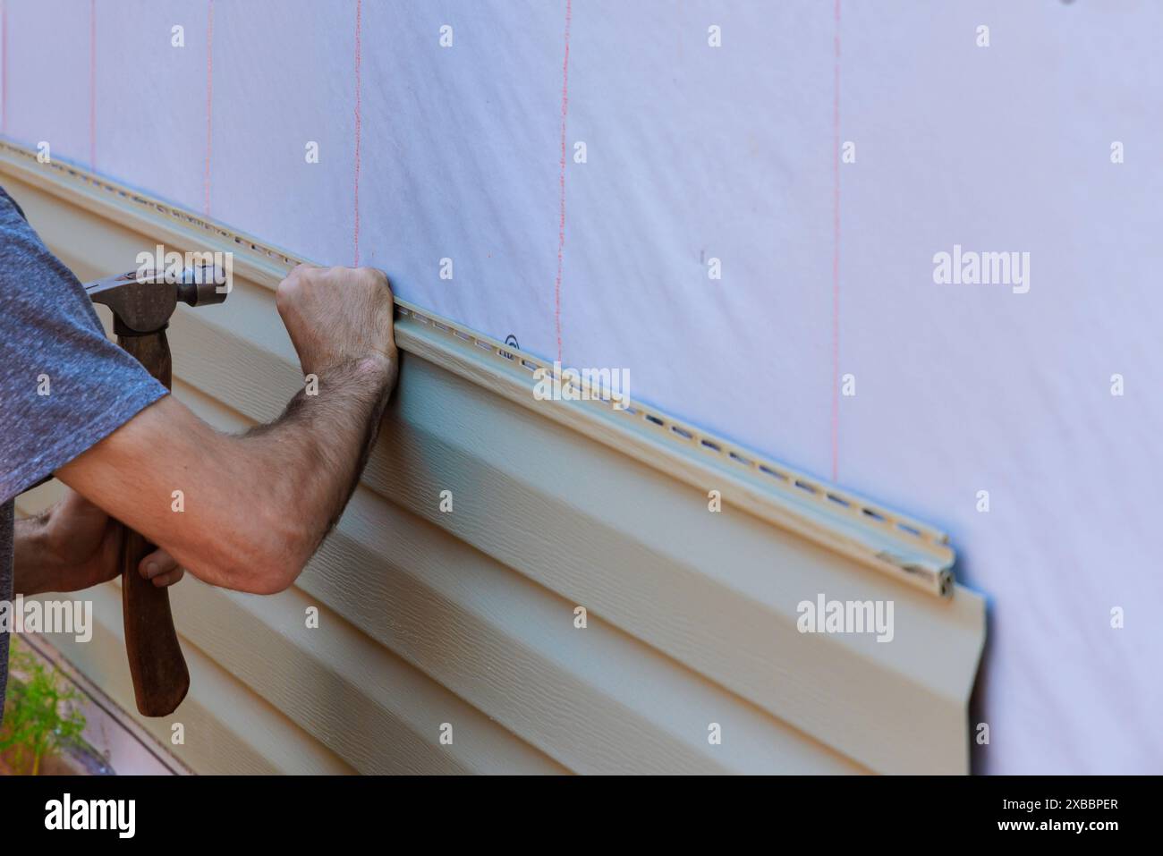 An installation of vinyl PVC siding by handyman during construction new ...