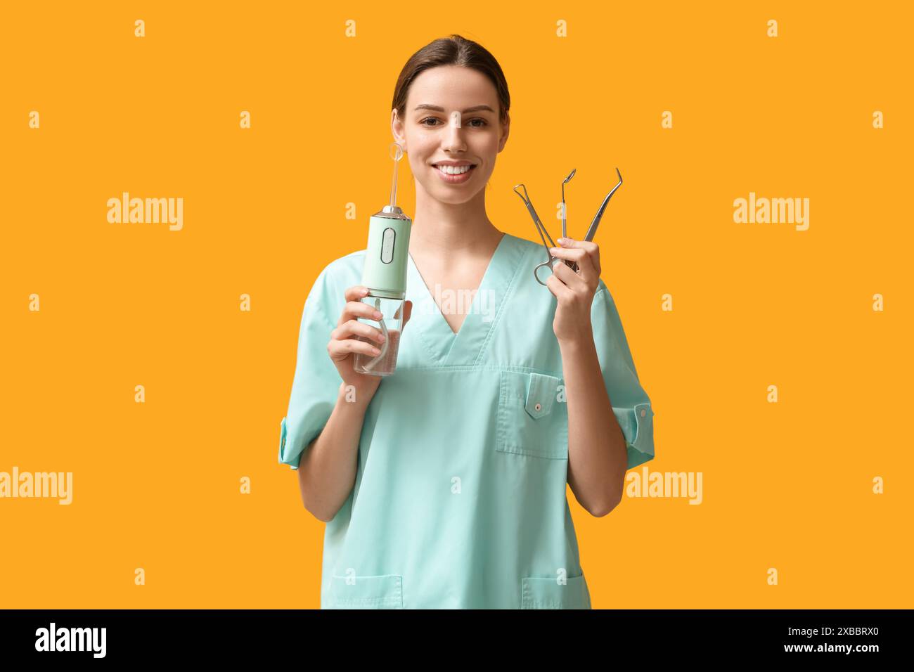 Female dentist with oral irrigator and tools on yellow background Stock ...