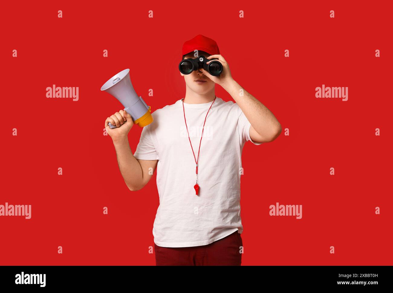 Male lifeguard with megaphone looking through binoculars on red ...