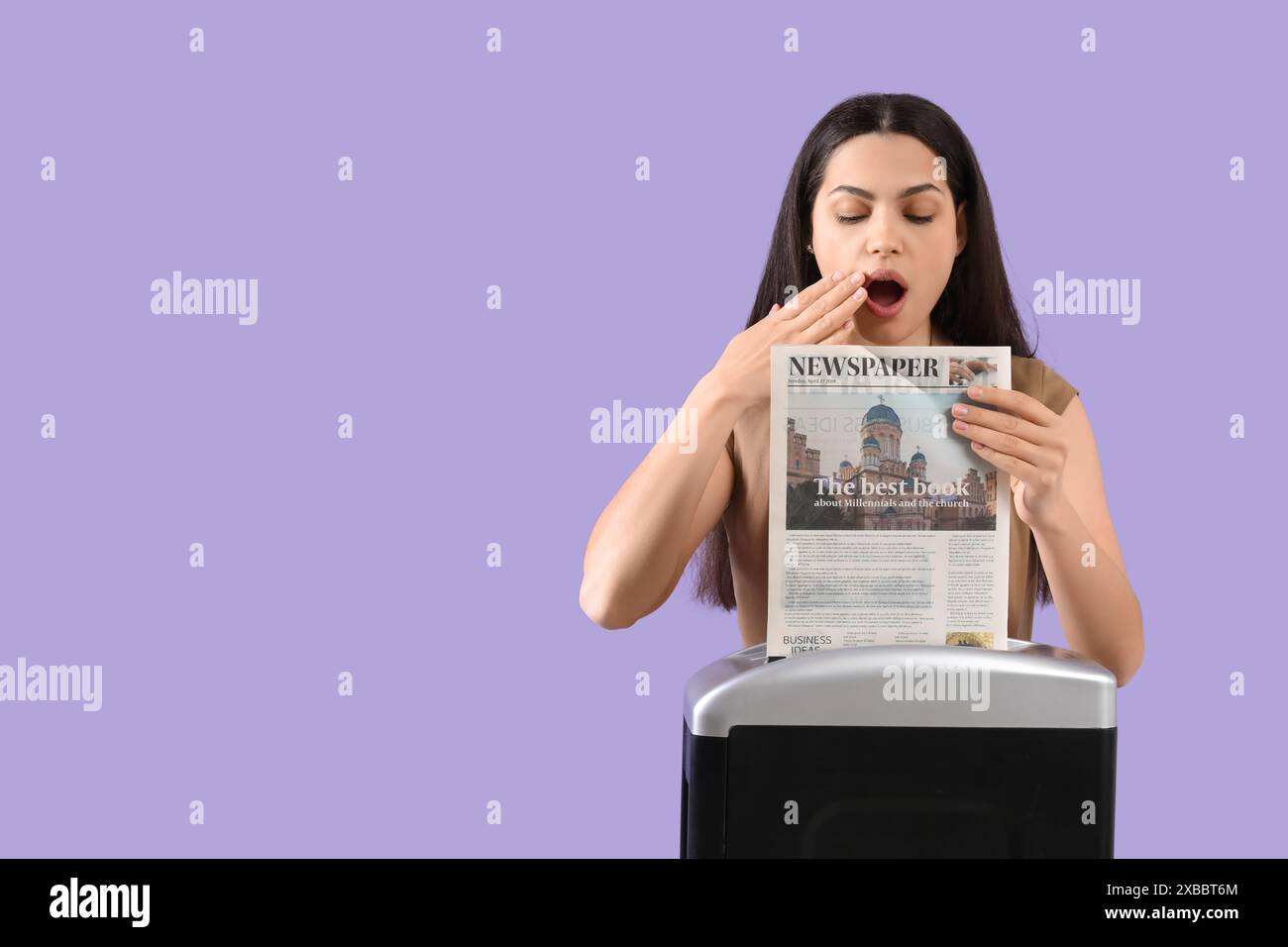 Shocked young woman destroying newspaper using shredder on lilac ...
