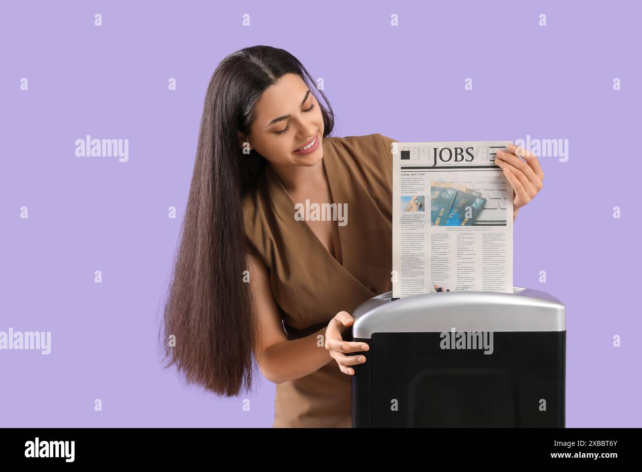 Happy young woman destroying newspaper using shredder on lilac ...