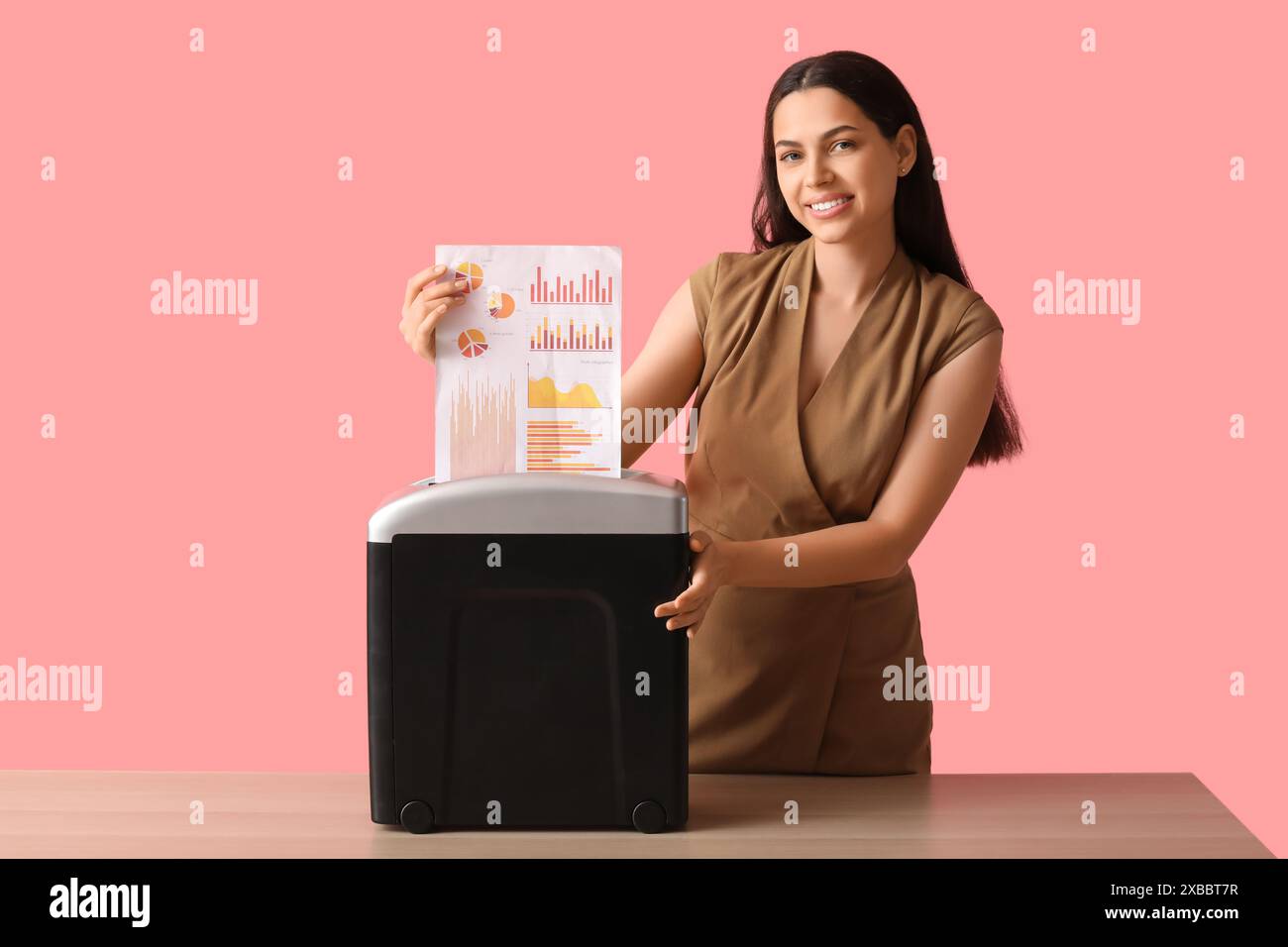 Happy young woman destroying documents using shredder on table against ...