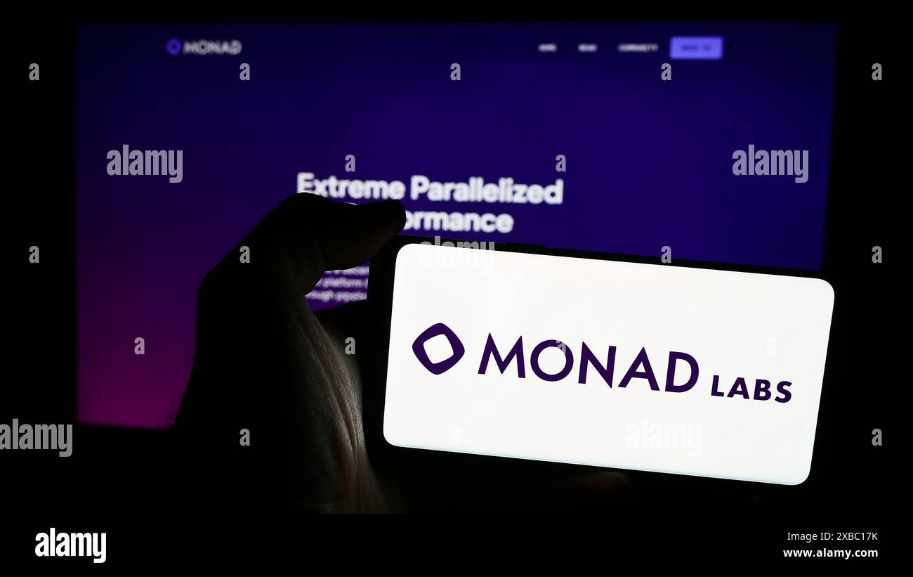 Person holding mobile phone with logo of American blockchain software company Monad Labs Inc. in ...