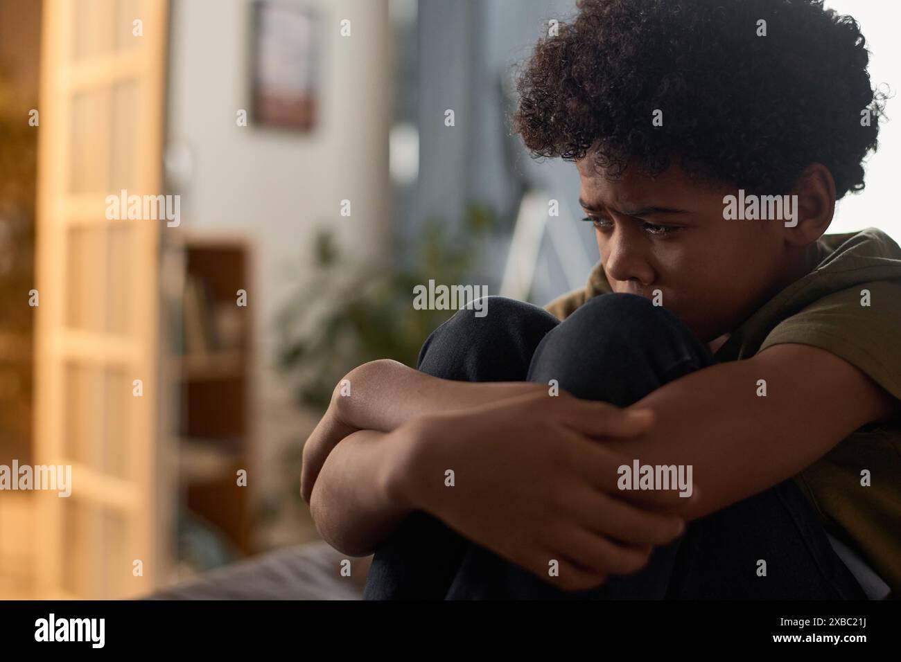 Side view portrait of scared young child crying and hugging knees ...